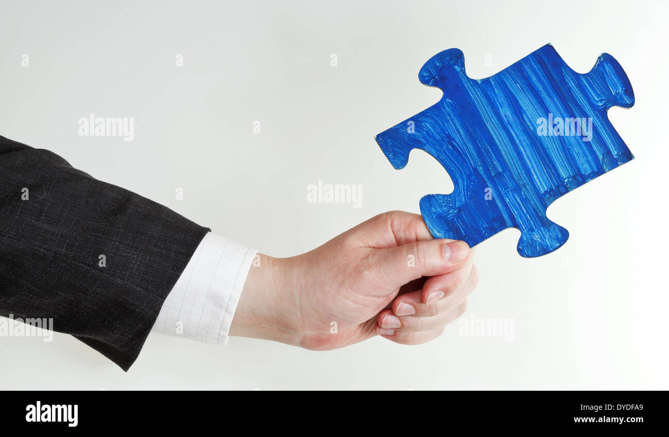 blue painted puzzle piece in male hand on grey background Stock Photo ...