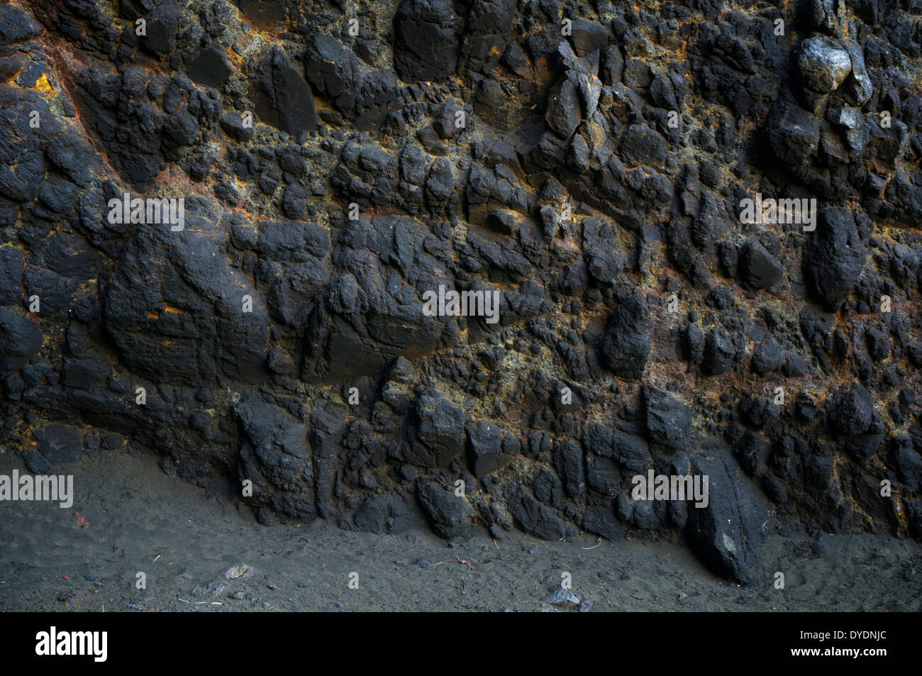 Black volcanic stone wall and sand at Karekare beach, Waitakere New ...