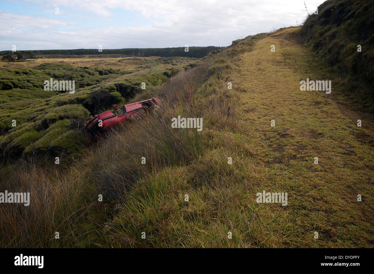 Over-turned car along very narrow stretch of road up a hillside close ...