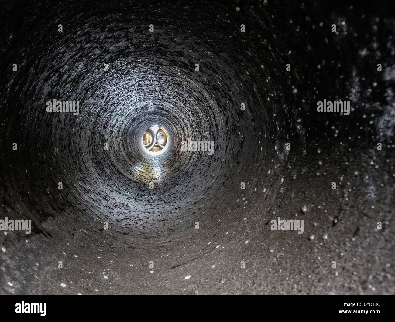 Looking through the inside of a black concrete industrial plumbing pipe ...