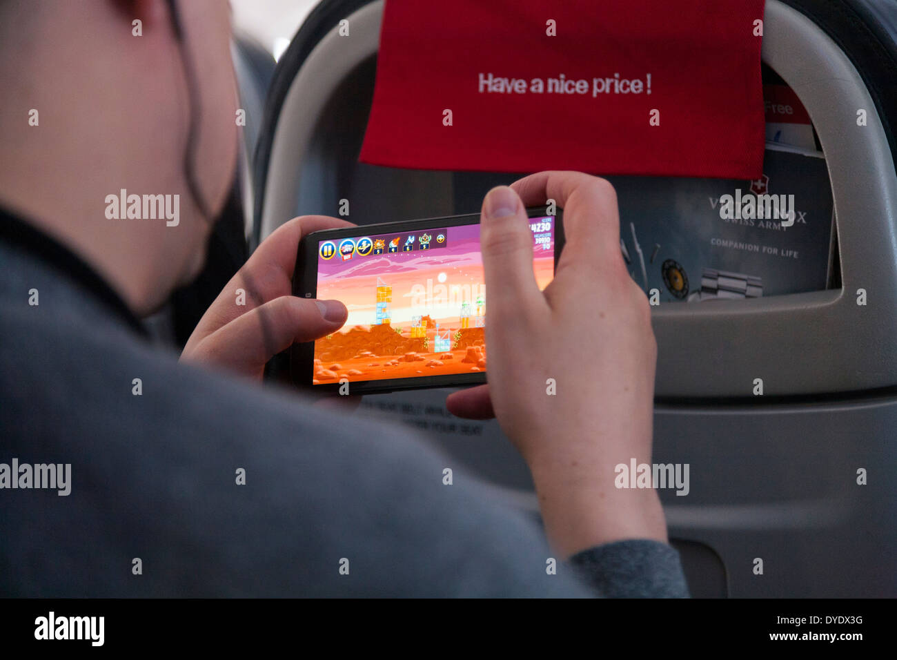 Male passenger playing a video game on his Samsung tablet computer ...