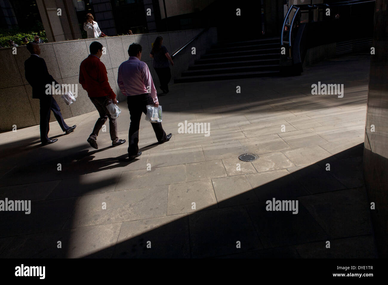 Three associates walk through area of City of London sunlight with ...