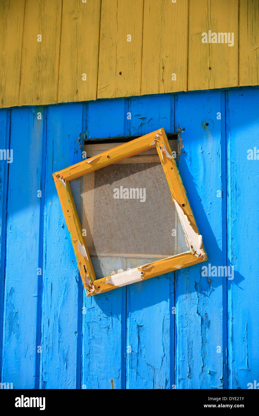 Blue and yellow window frame falling off beach hut Stock Photo - Alamy