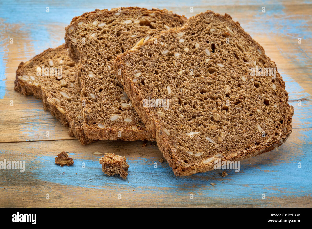 slices of organic, whole grain, dark rye bread on painted wooden ...