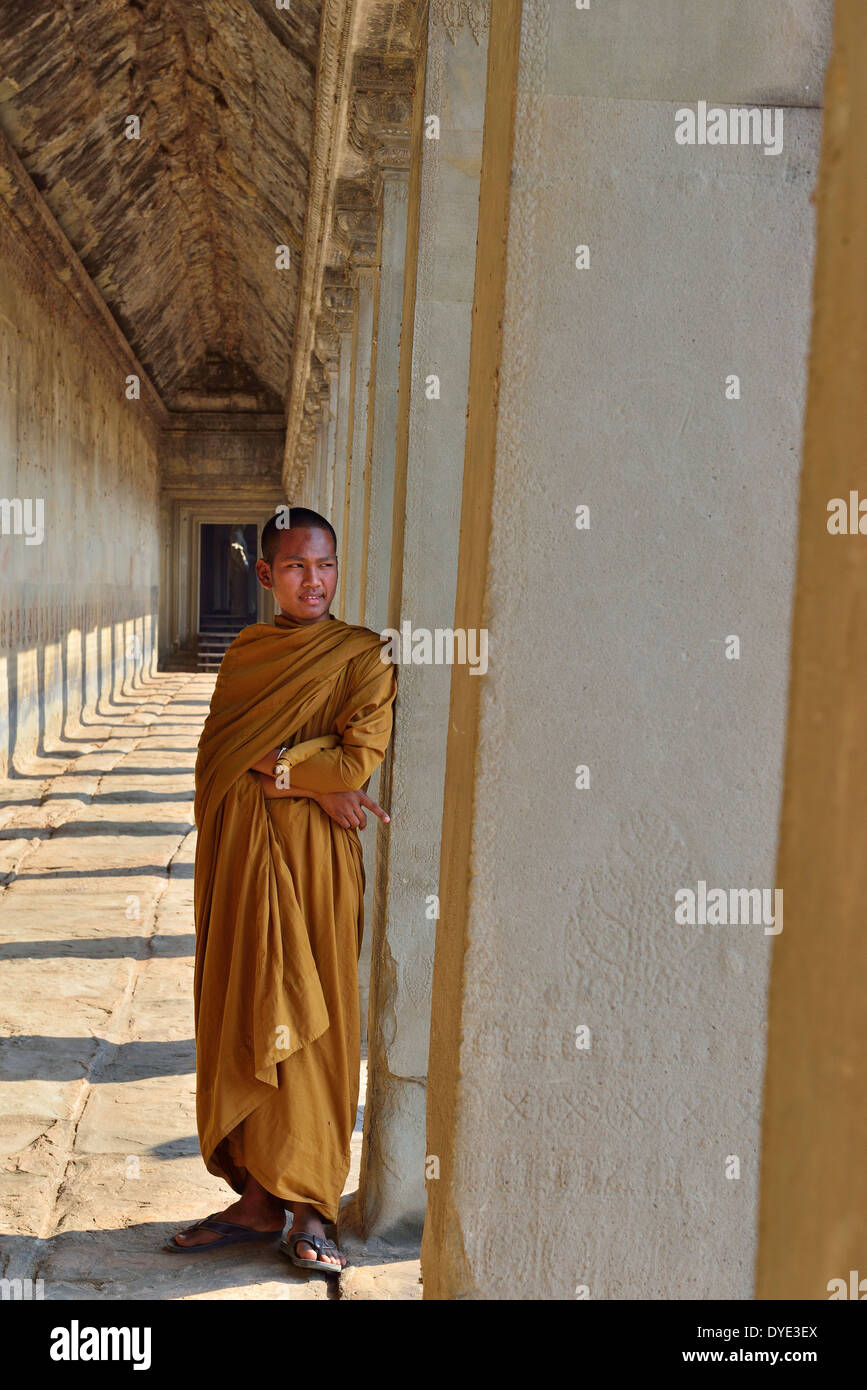 Visiting monk in yellow standing among the bas-relief scenes from the ...