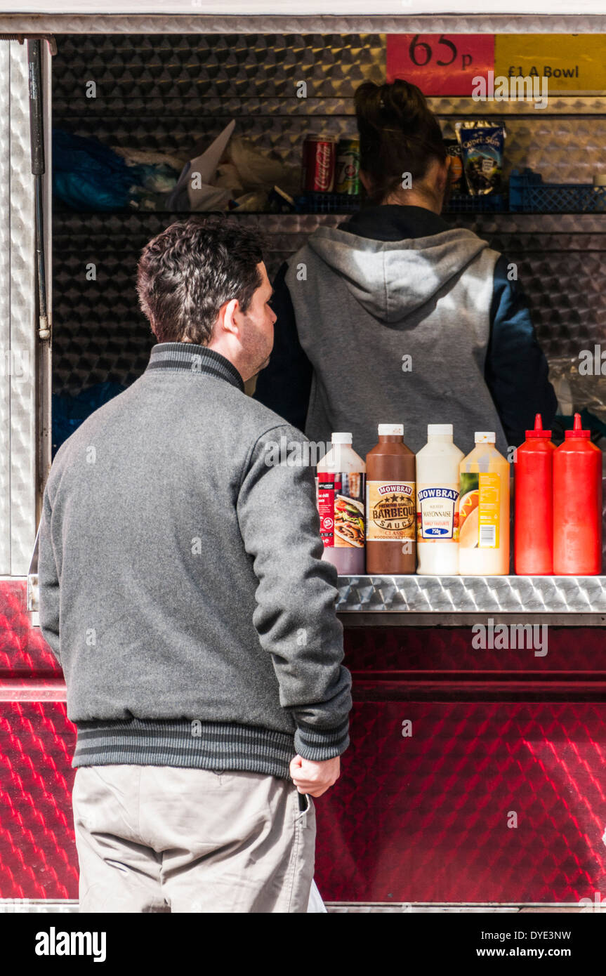 Man waiting at a fast food unit whilst a girl prepares his order in the ...