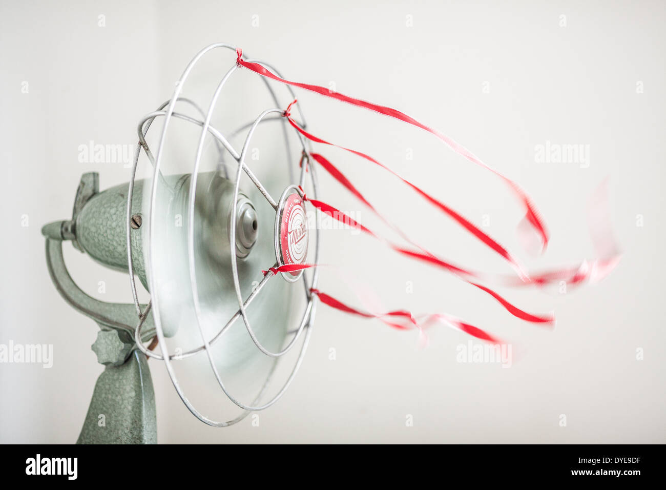 An old green desk fan with red ribbons against a white background Stock ...