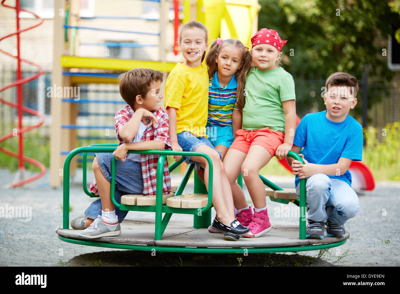Image of little friends sitting on carousel on playground Stock Photo ...