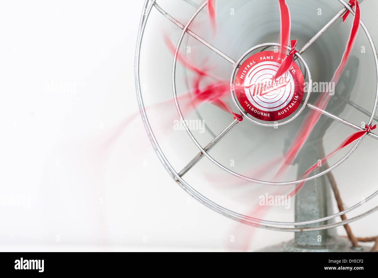 An old green desk fan with red ribbons against a white background Stock ...