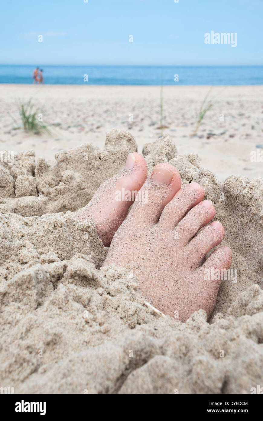 Feet buried in sand with uncovered toes on a beach Stock Photo - Alamy