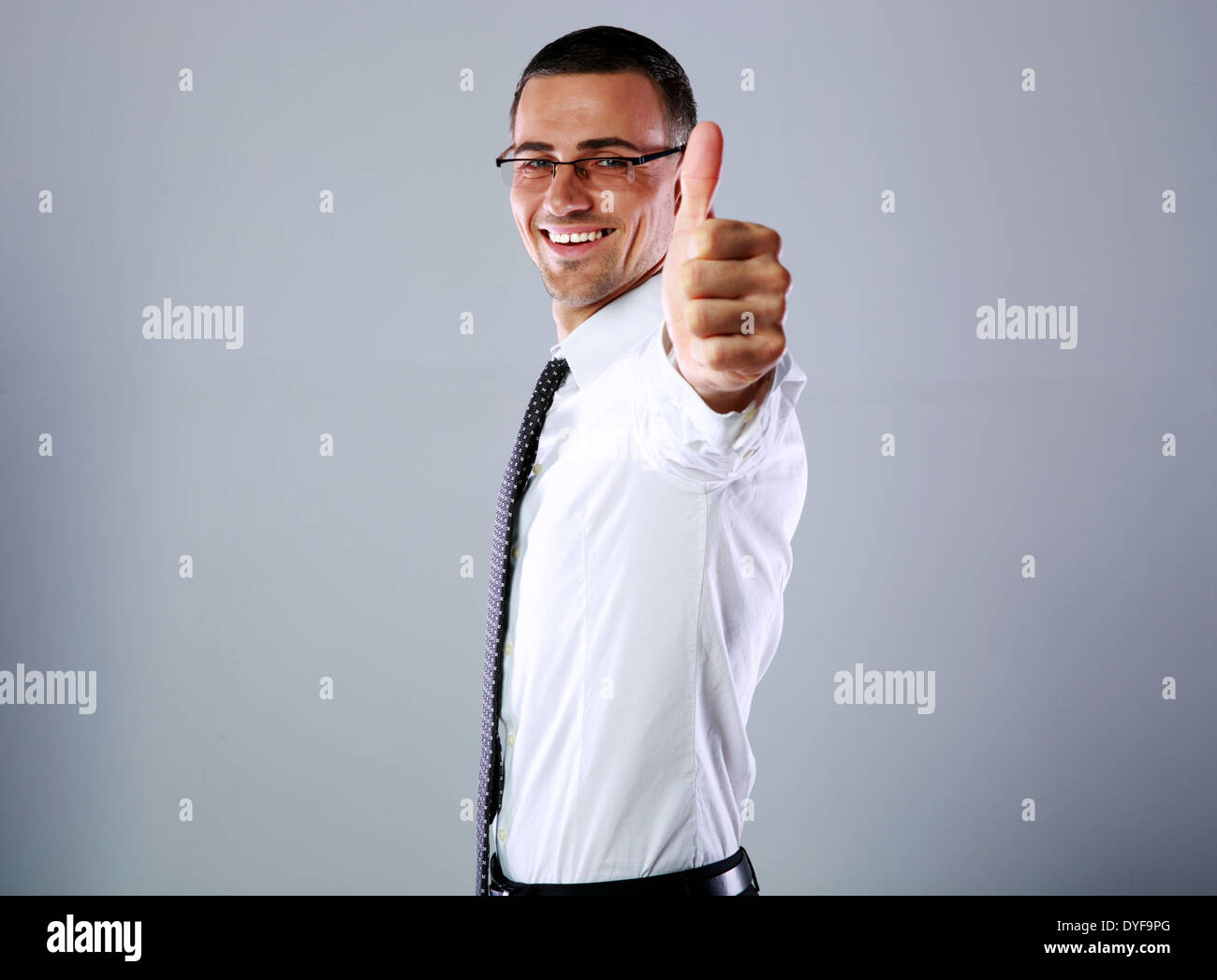 Side view portrait of a happy businessman showing thumb up over gray ...