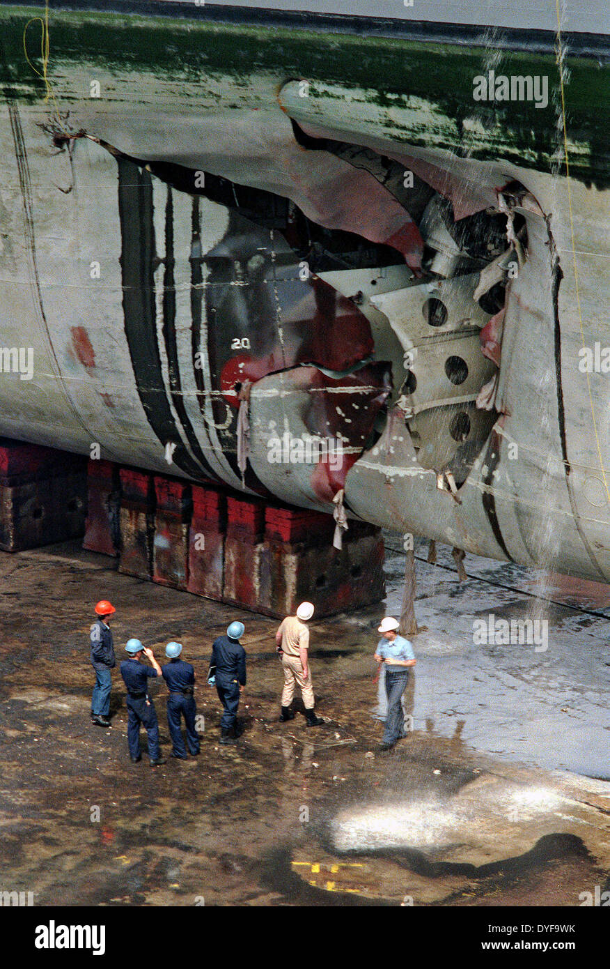 Repair crews inspect the damage to the hull of the amphibious assault ...