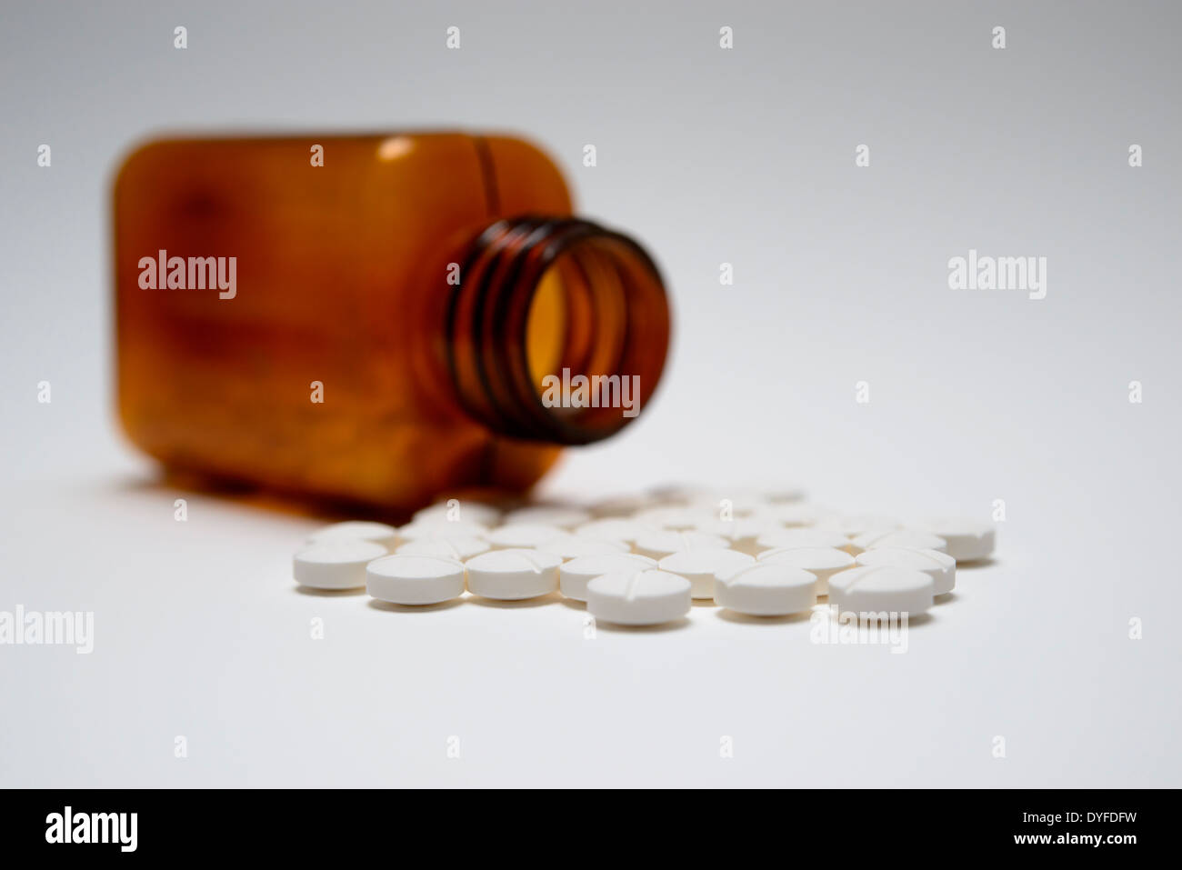 Generic white pills on a white background, spilled from a brown plastic ...