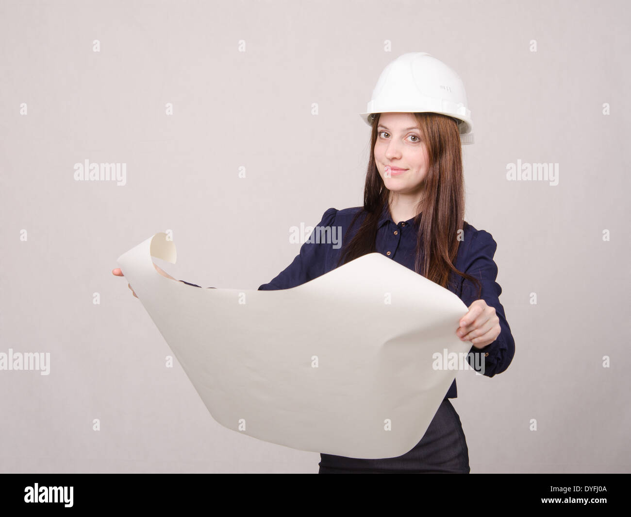 Young woman architect in hardhat standing with blueprints in hand Stock ...
