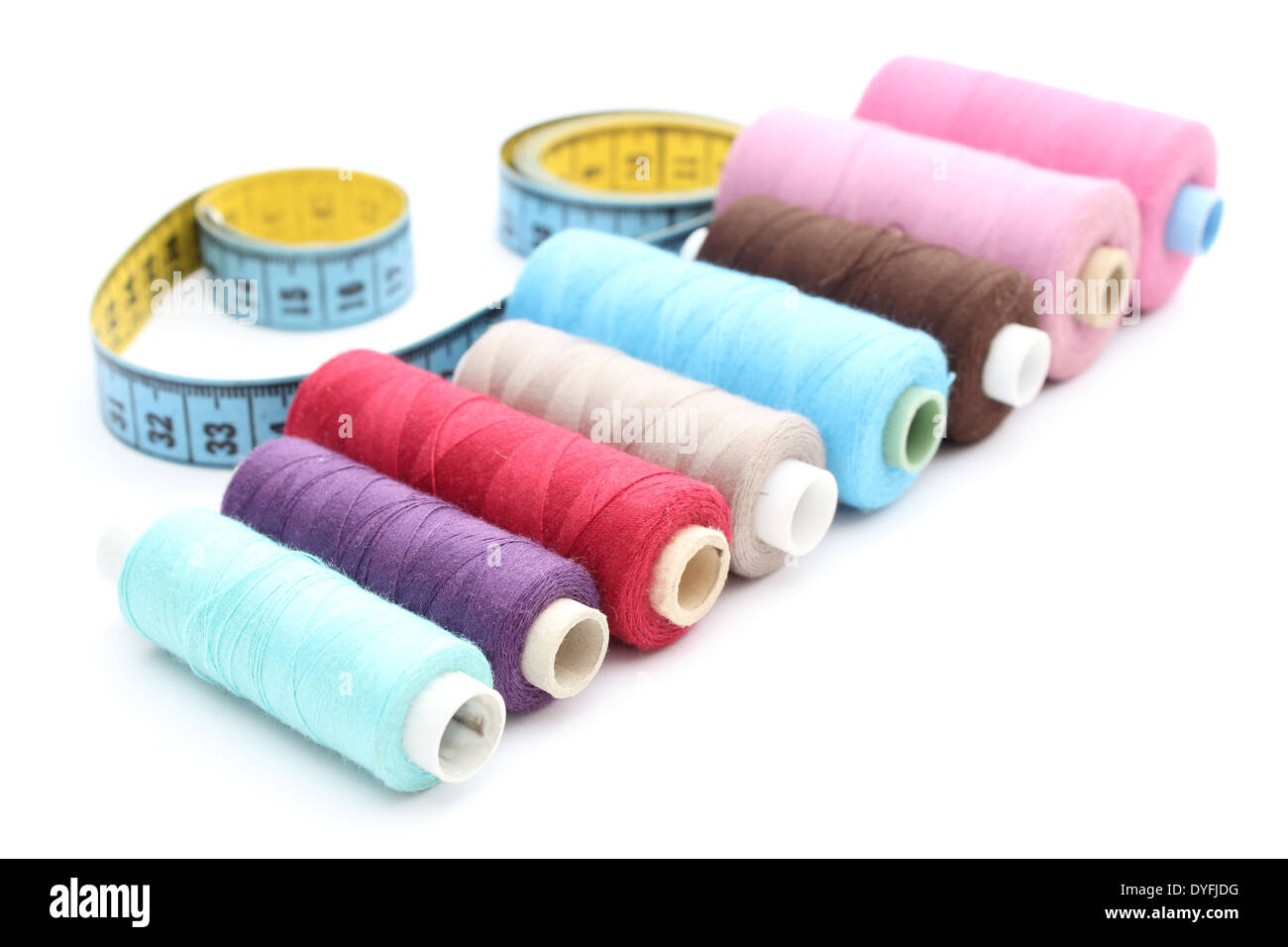 Colorful spools of thread with a tape measure isolated on white ...