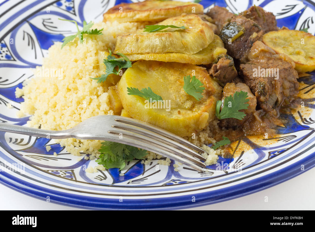 Moroccan sweet potato and beef tagine closeup on a plate with a fork. A ...