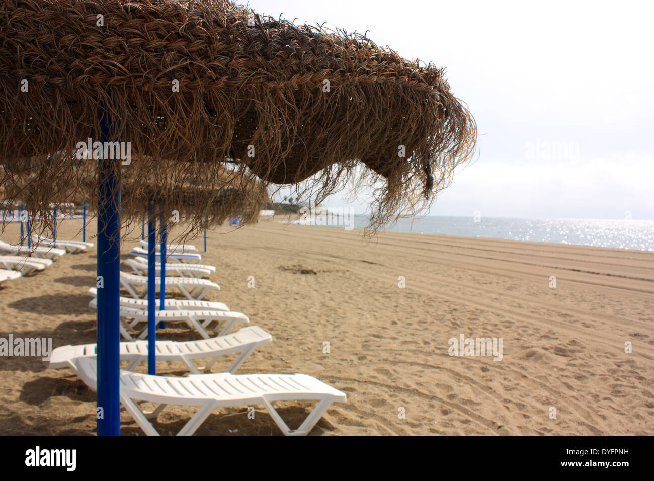 A view of a straw roofed umbrella on a beach in Spain Stock Photo - Alamy