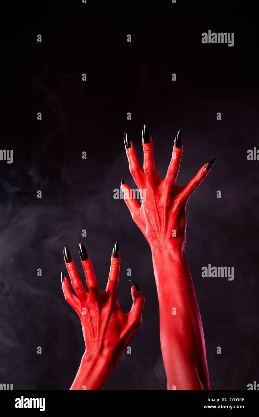 Horror red devil hands with black nails on smoky background, studio ...