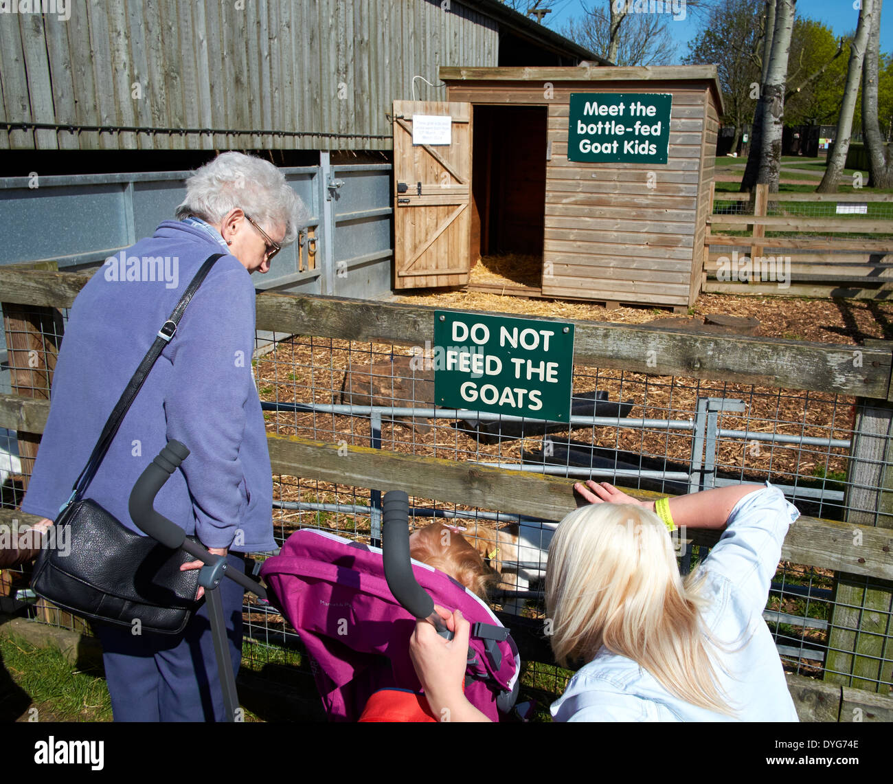 People in front of a Do not feed the goats sign. White post farm ...