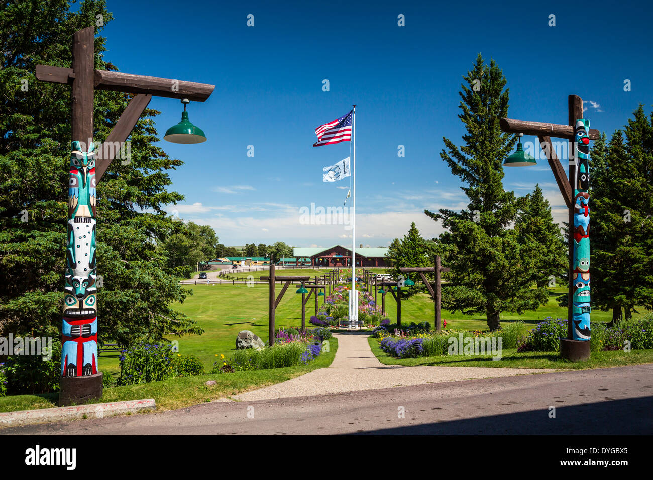 A totem pole with flags and flower garden at the Glacier Park Lodge in ...