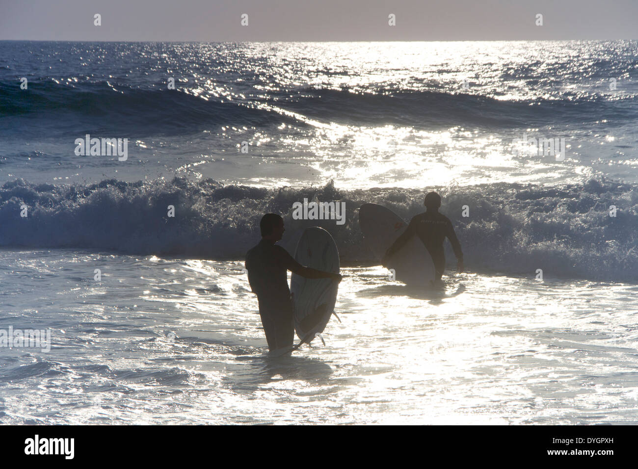 Two surfers heading out into the waves Stock Photo - Alamy