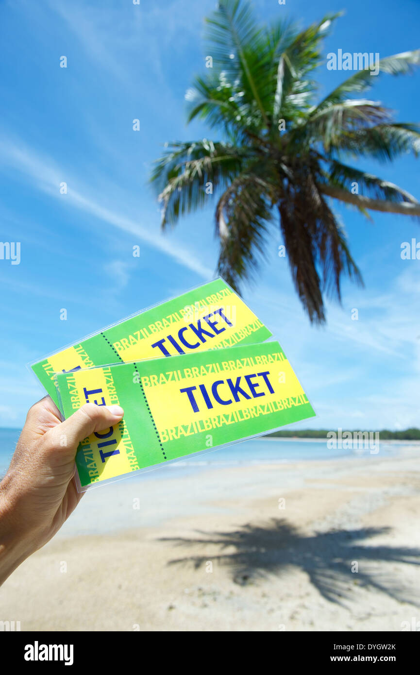 Hand holding pair of Brazil tickets in front of tropical palm tree on ...