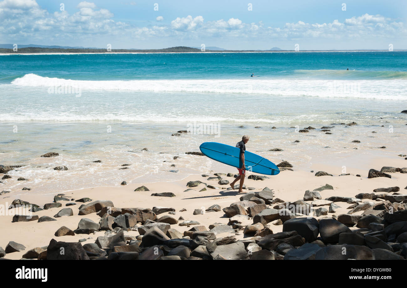 Surfer carries his blue surfboard towards the surf at the Noosa Surf ...