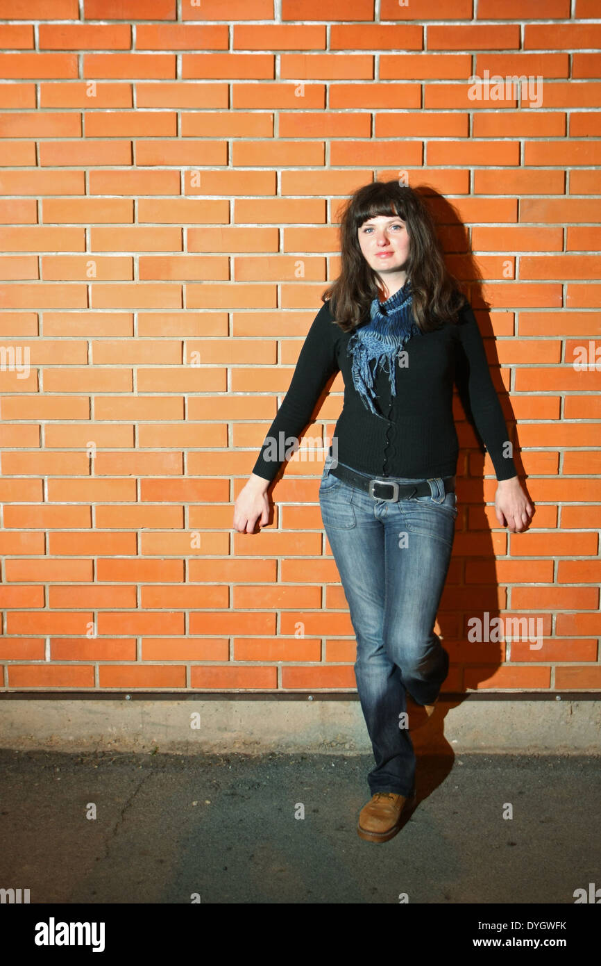 A young woman posing in front of a brick wall Stock Photo - Alamy