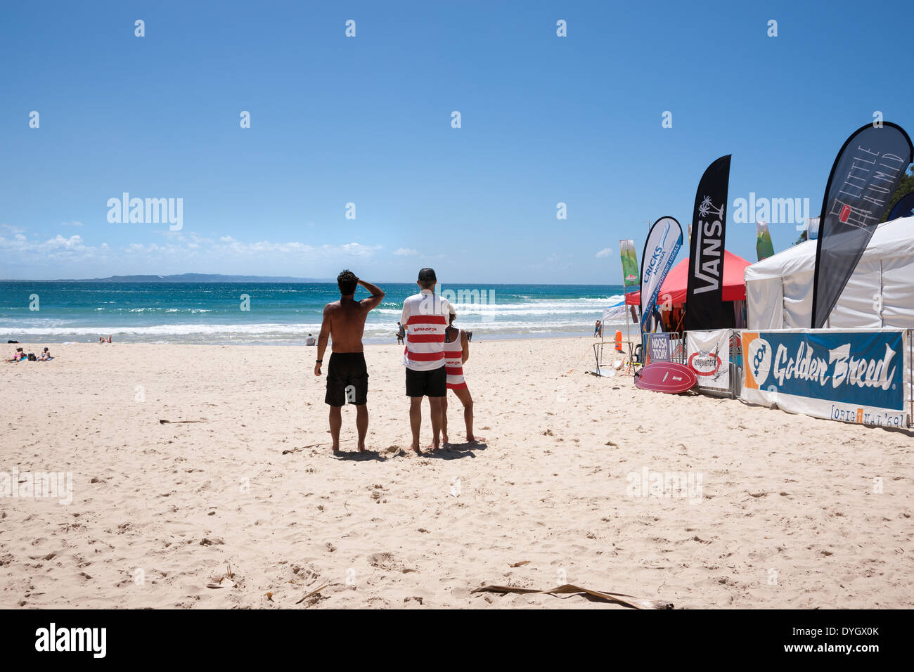 Three spectators stand looking out to the contestant in the Noosa ...