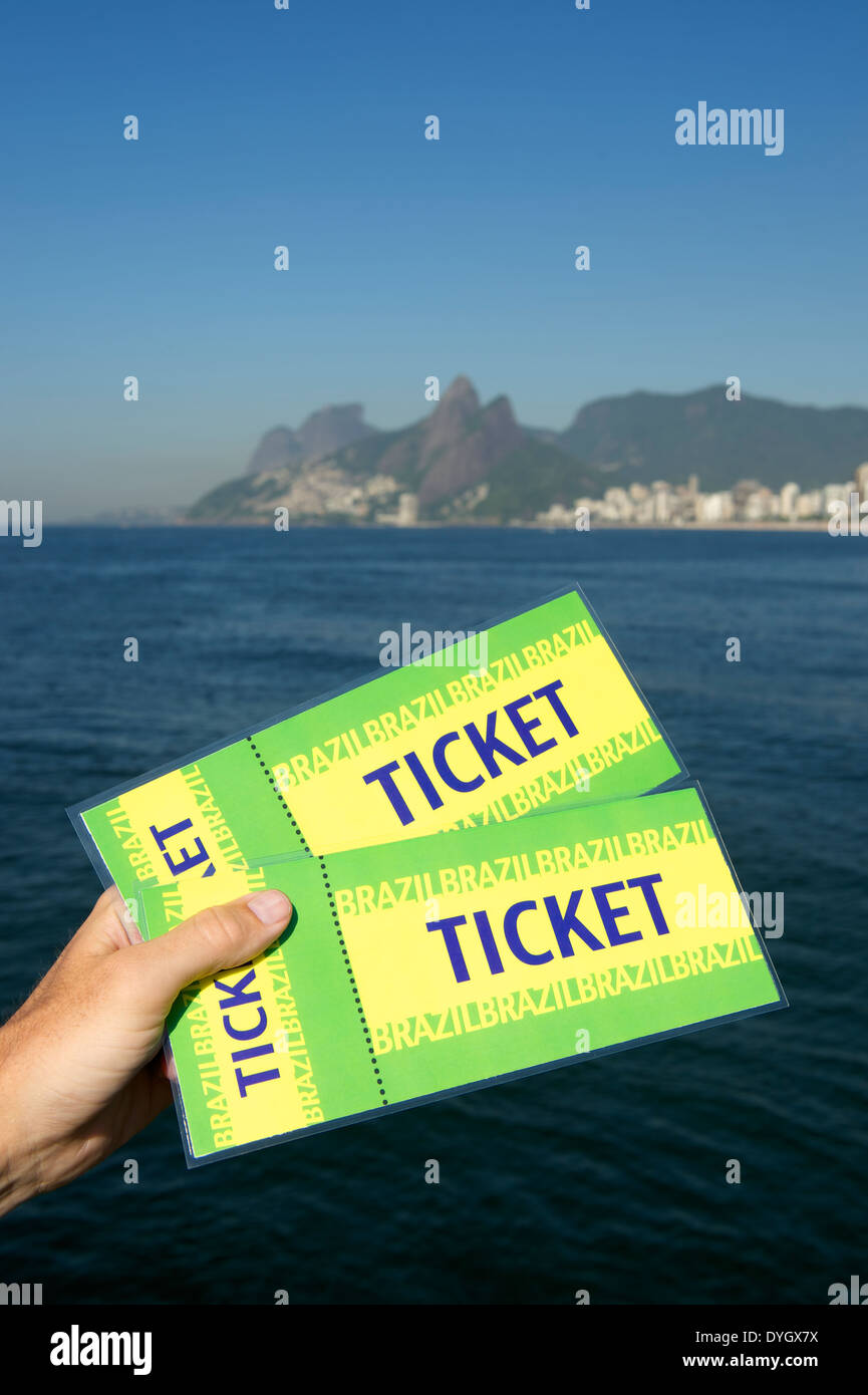 Hand holding pair of Brazil tickets in front of sea view Ipanema Beach ...