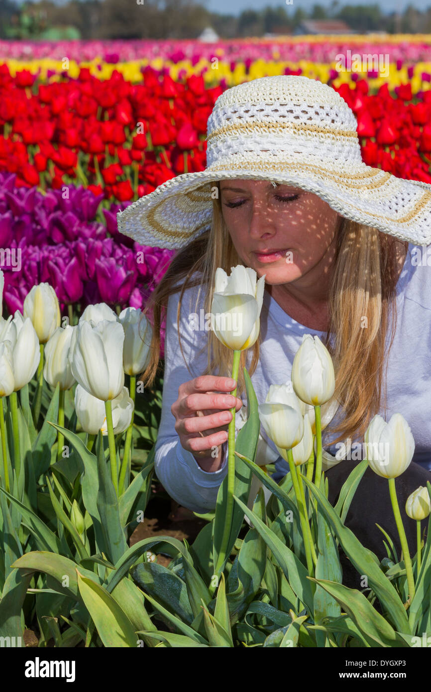 beautiful caucasian woman smiling and holding flowers in tulip field ...