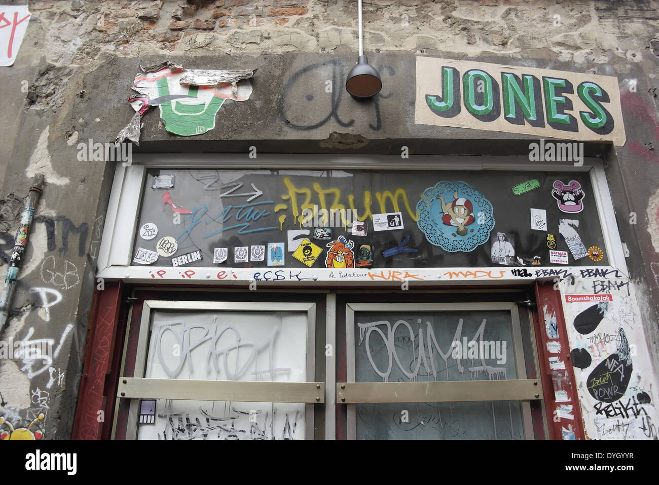 Graffiti scrawl paste-ups on, around wood frame window in grey plaster ...