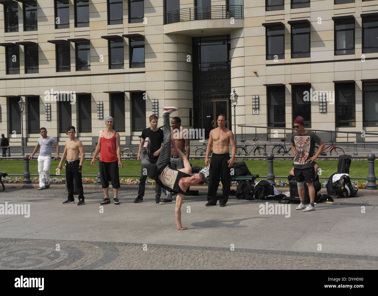 Seven male dancers watching one man acrobatic dancing, balancing on one ...