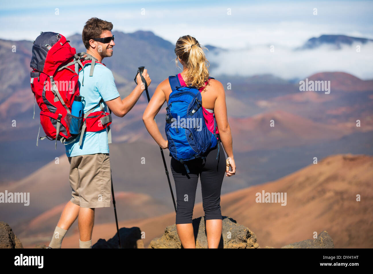 Two hikers relaxing enjoying the amazing view from the mountain top ...