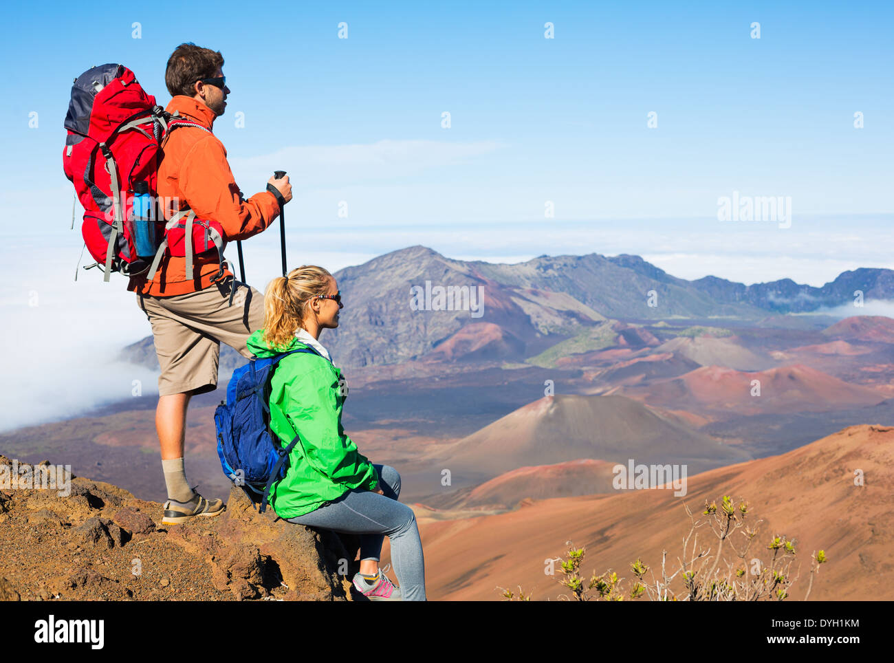 Two hikers relaxing enjoying the amazing view from the mountain top ...
