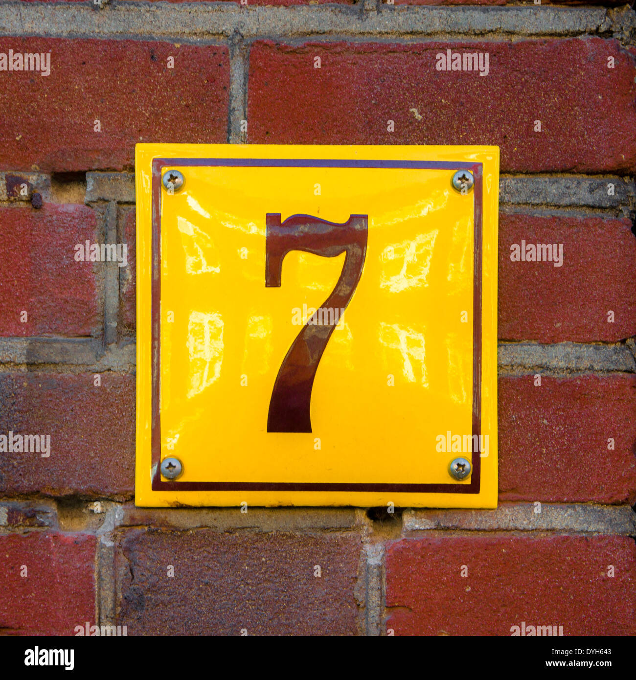 Enameled house number seven. Brown lettering on a yellow background ...