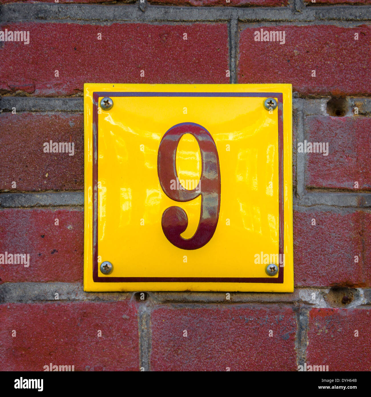 Enameled house number nine. Brown lettering on a yellow background ...
