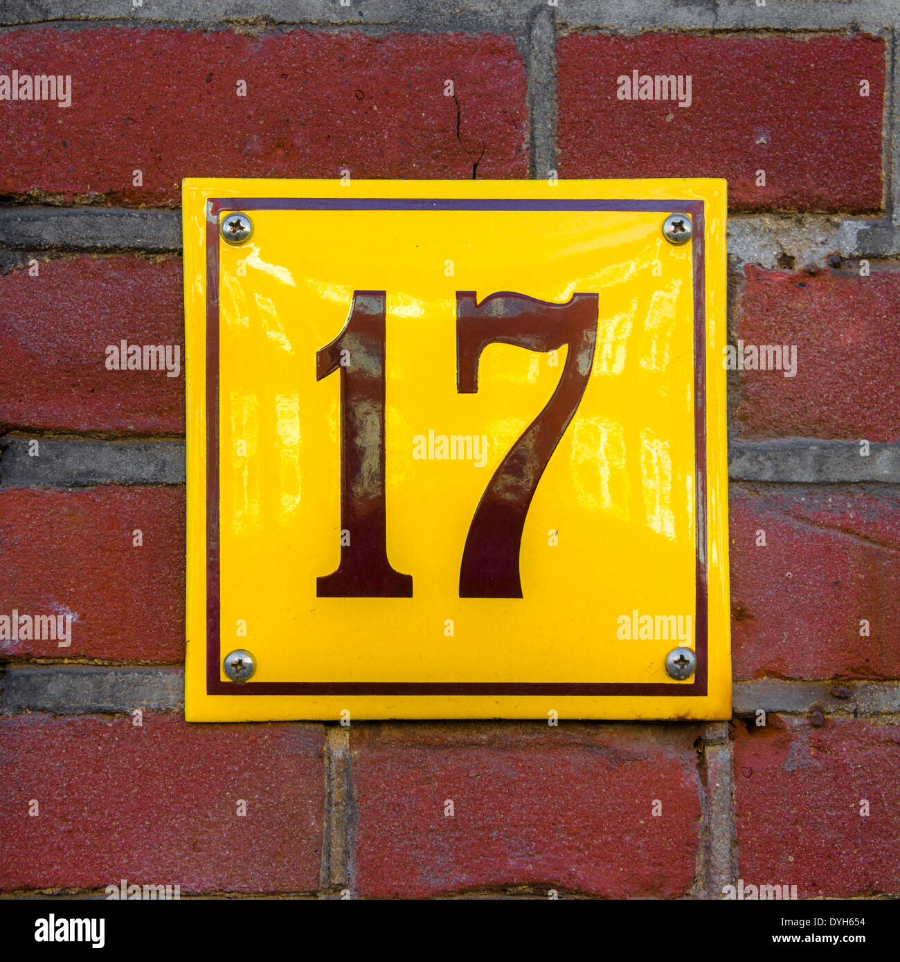 Enameled house number seventeen. Brown lettering on a yellow background ...