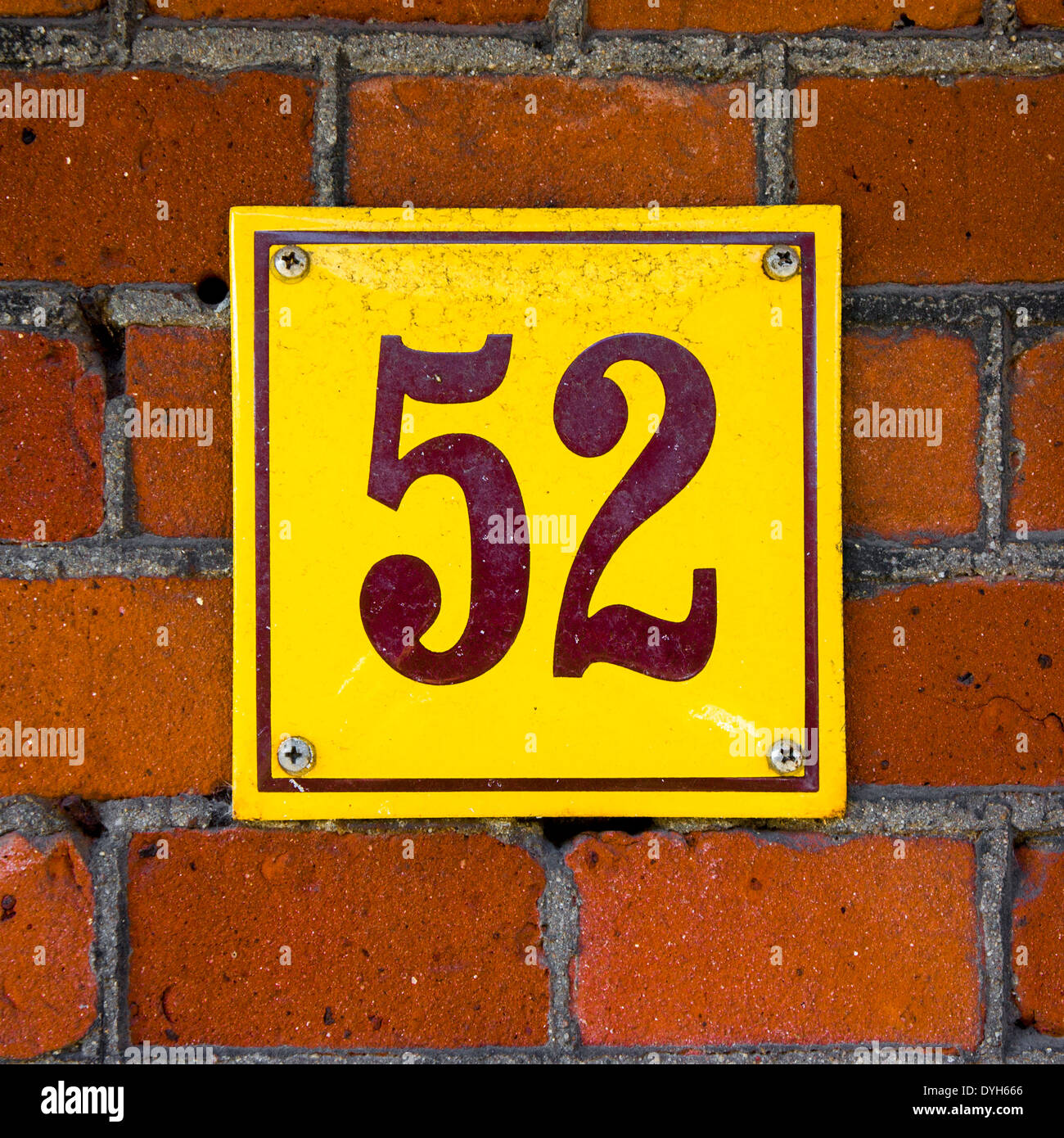 Enameled house number fifty two. Brown lettering on a yellow background ...