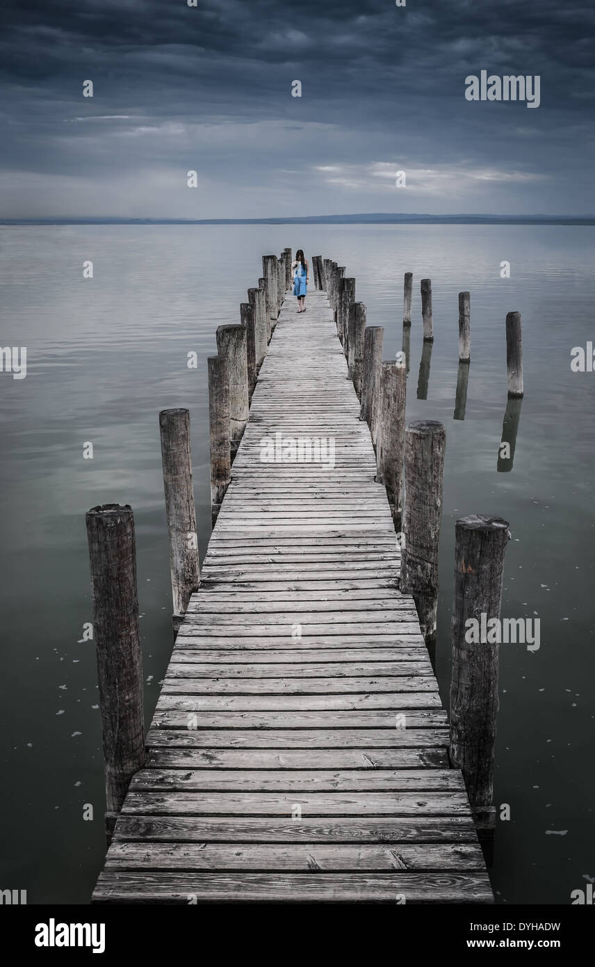 Scary longhaired girl in blue dress walking on the pier in eerie ...