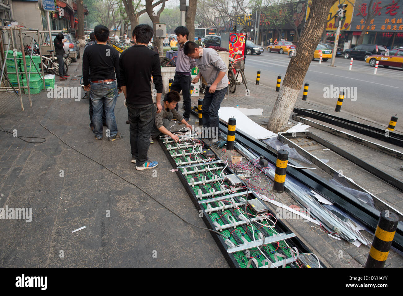 Beijing, China. 14th Apr, 2014. Young men assemble a neon sign for a ...