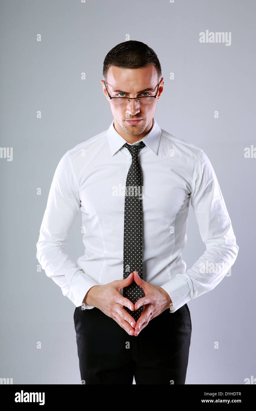 Handsome businessman folding his hands together on gray background ...