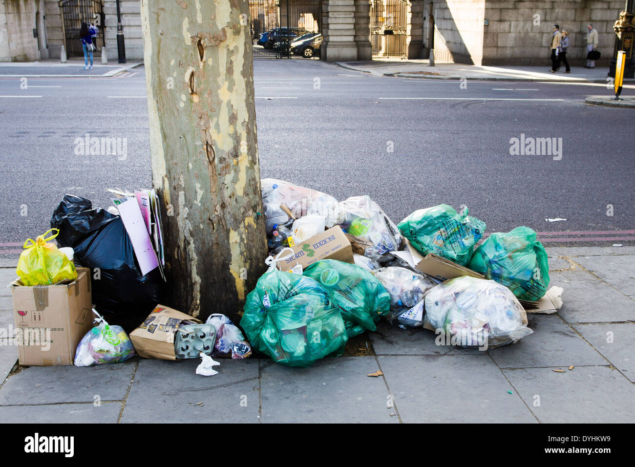 Rubbish/trash heaped up in bags under a tree on a pavemnet, London ...