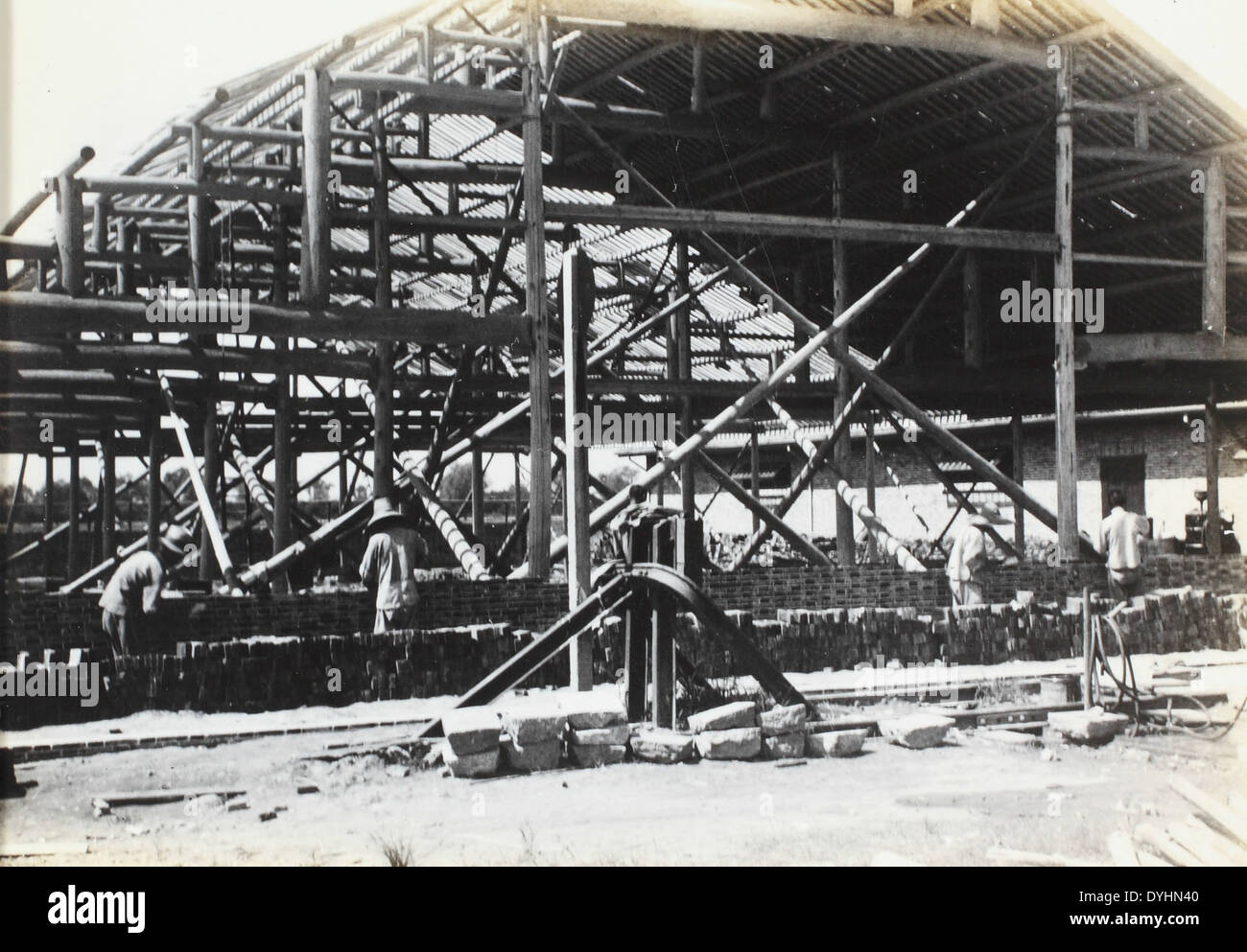 This image shows a factory exterior with workers in the early to mid ...