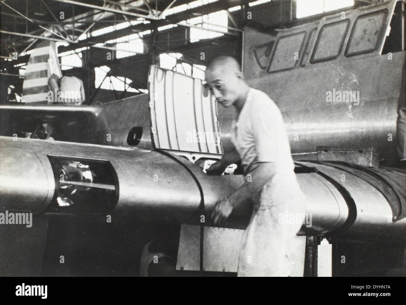 A worker assembles an aircraft in a factory, showcasing the labor and ...