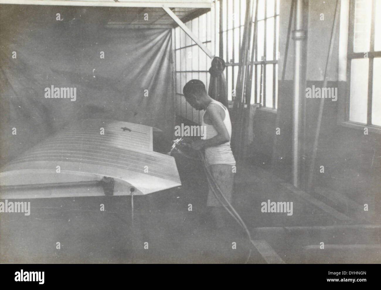 This photograph captures a factory worker engaged in welding, an ...