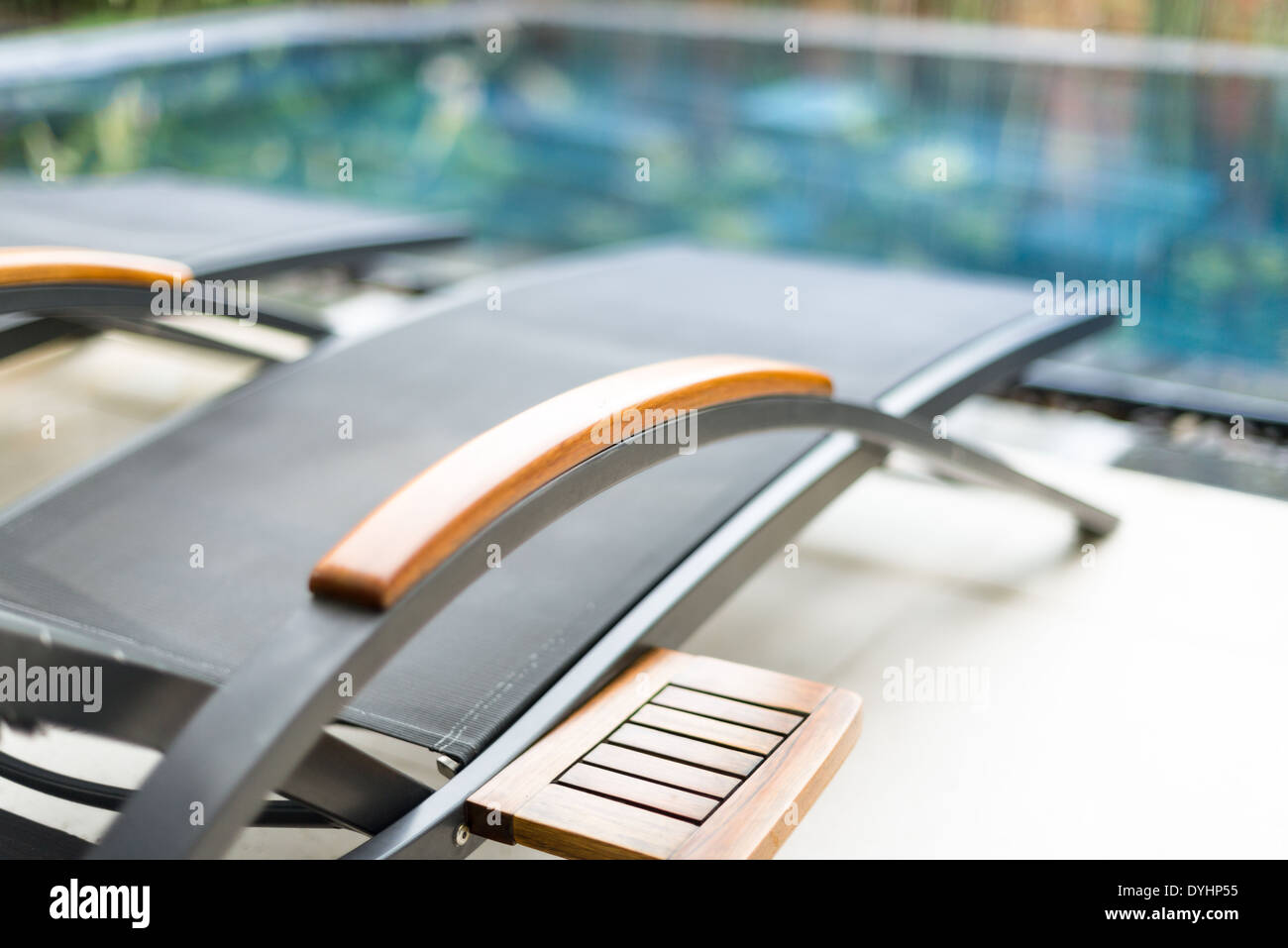 Empty metal chaise lounges in hotel area. Blurry swimming pool with ...