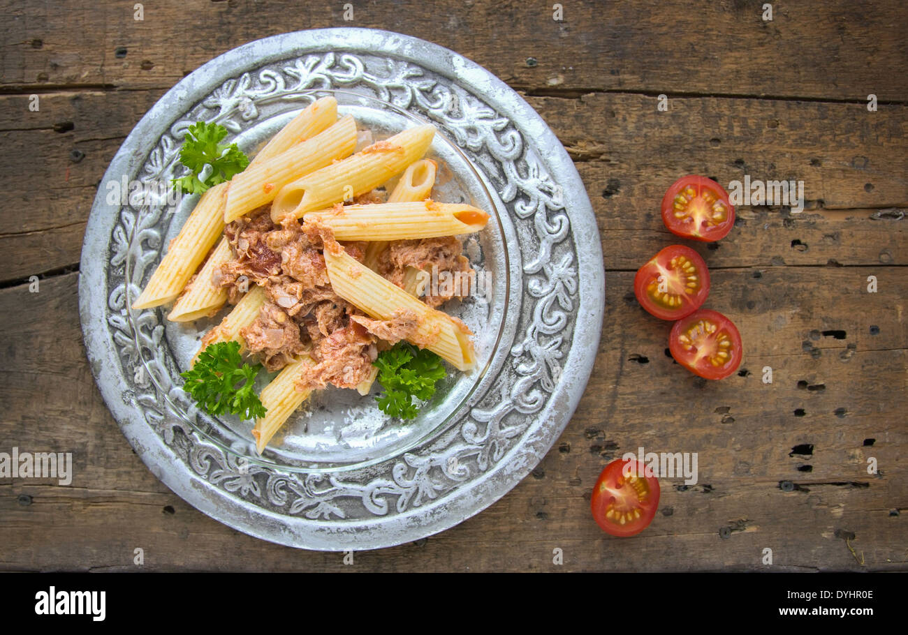 Penne pasta with tuna sauce in silver plate on old wood Stock Photo - Alamy