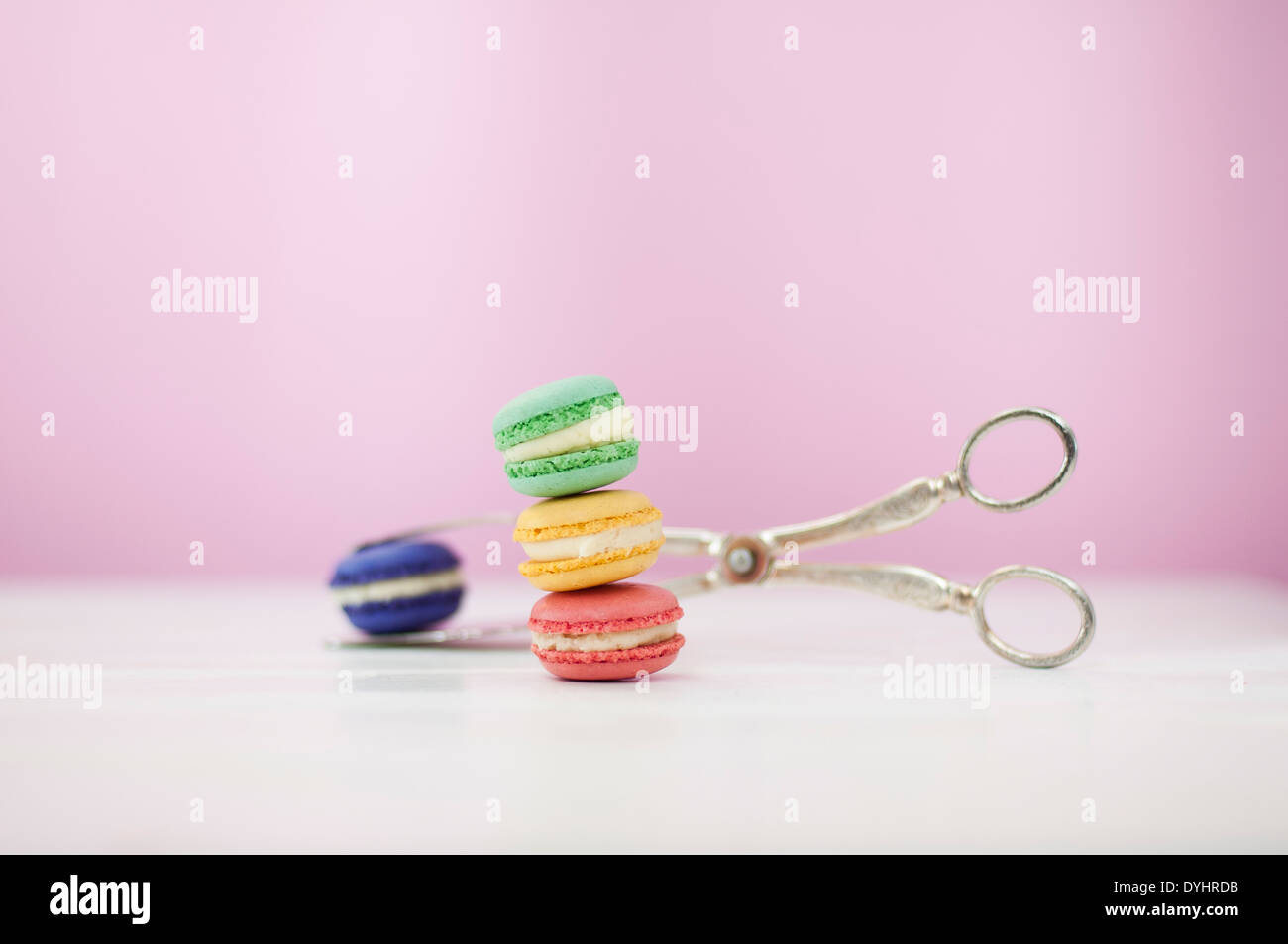 Colorful Macaroon Cookies with Silver Tongs Against Pink Background ...