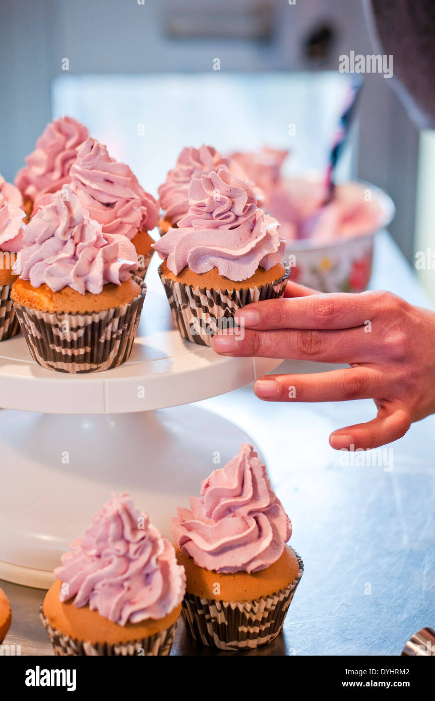 Hand Placing Cupcakes with Icing on Cake Platter Stock Photo - Alamy